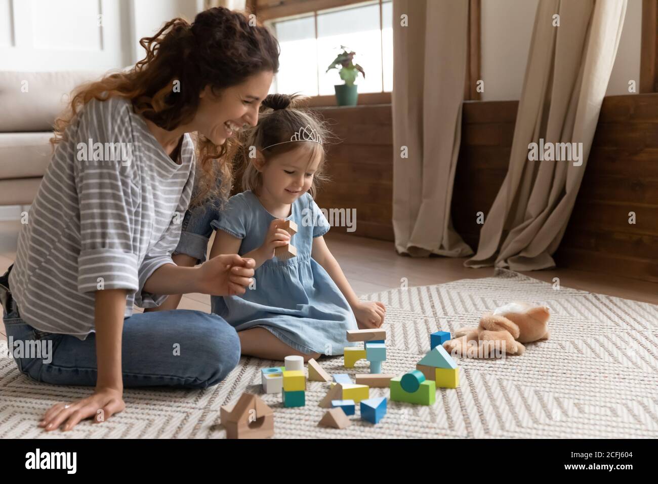 Mom and daughter play with color wooden bricks toys set Stock Photo - Alamy