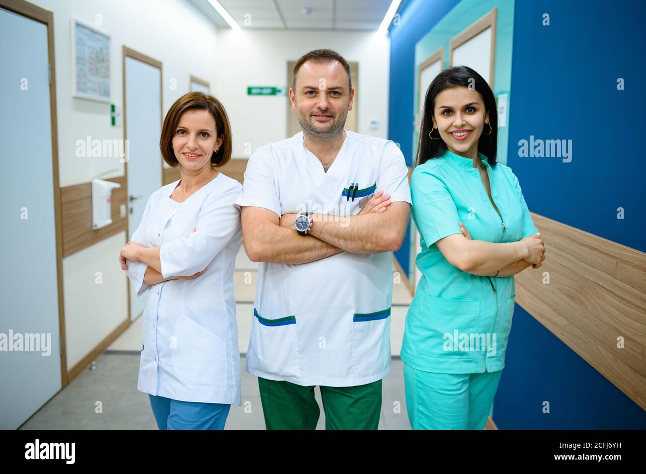 Three smiling doctors standing in clinic corridor Stock Photo - Alamy