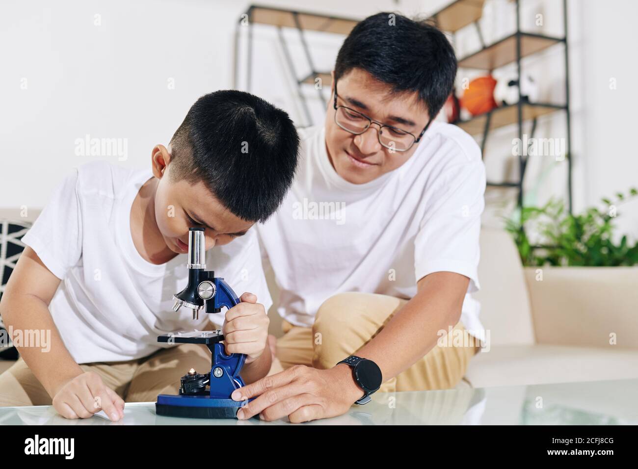 Dad showing microscope to son Stock Photo - Alamy