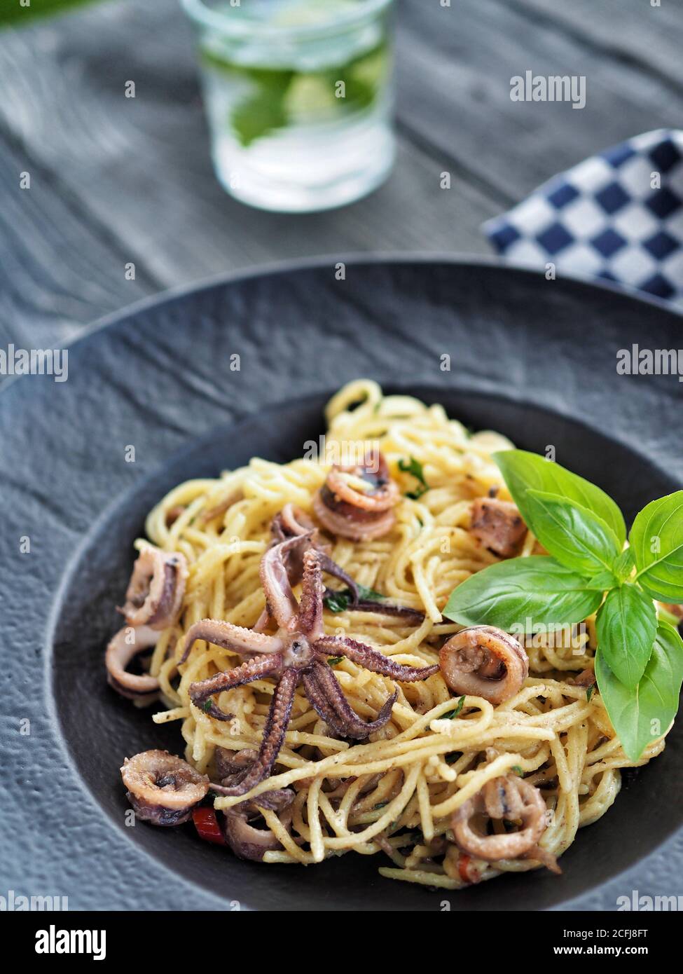 Spaghetti with calamari. Seafood pasta with green basil in black plate ...