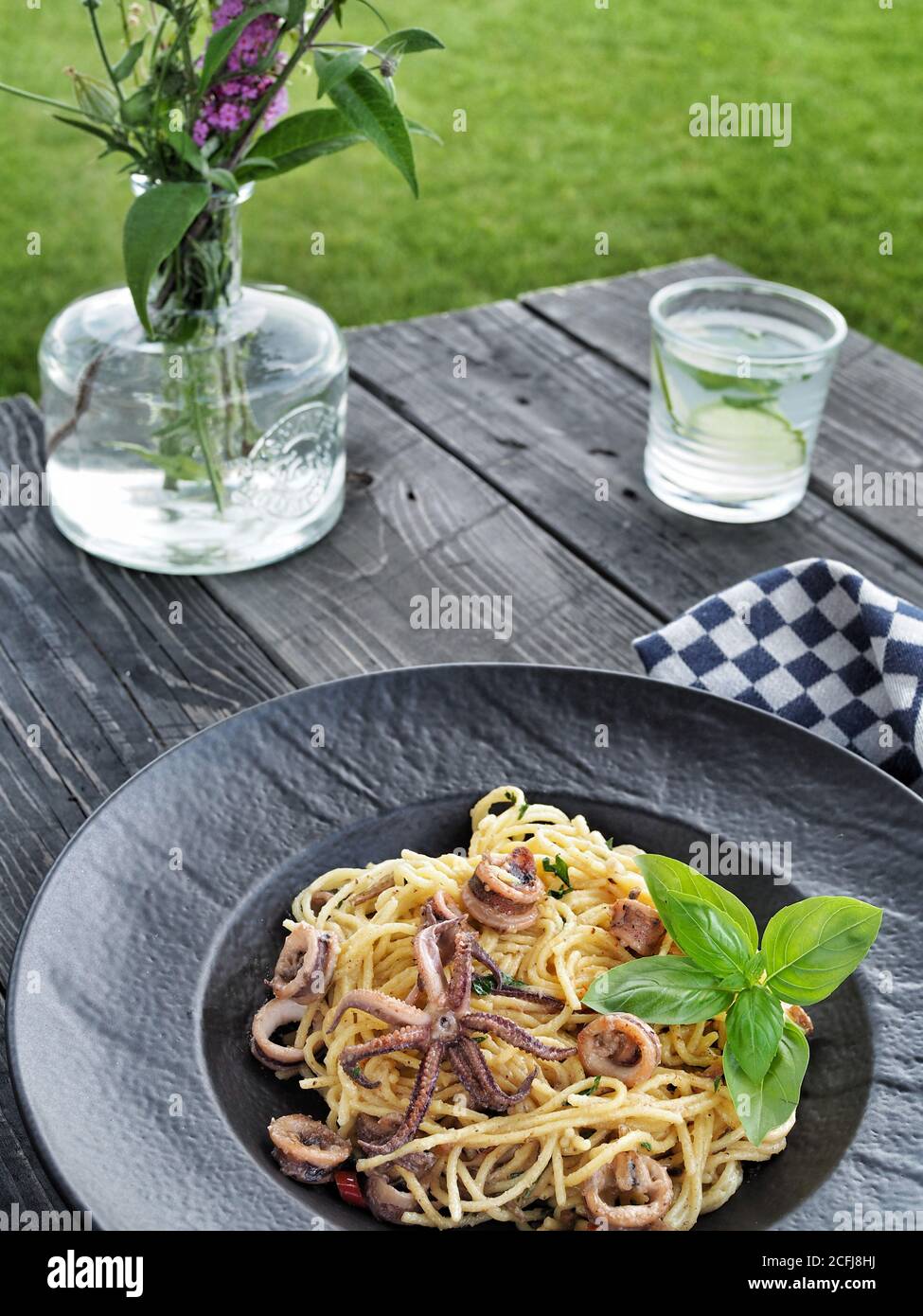 Spaghetti with calamari. Seafood pasta with green basil in black plate ...