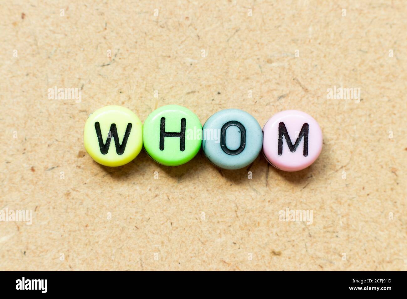 Round color bead with black letter in word whom on wood background ...