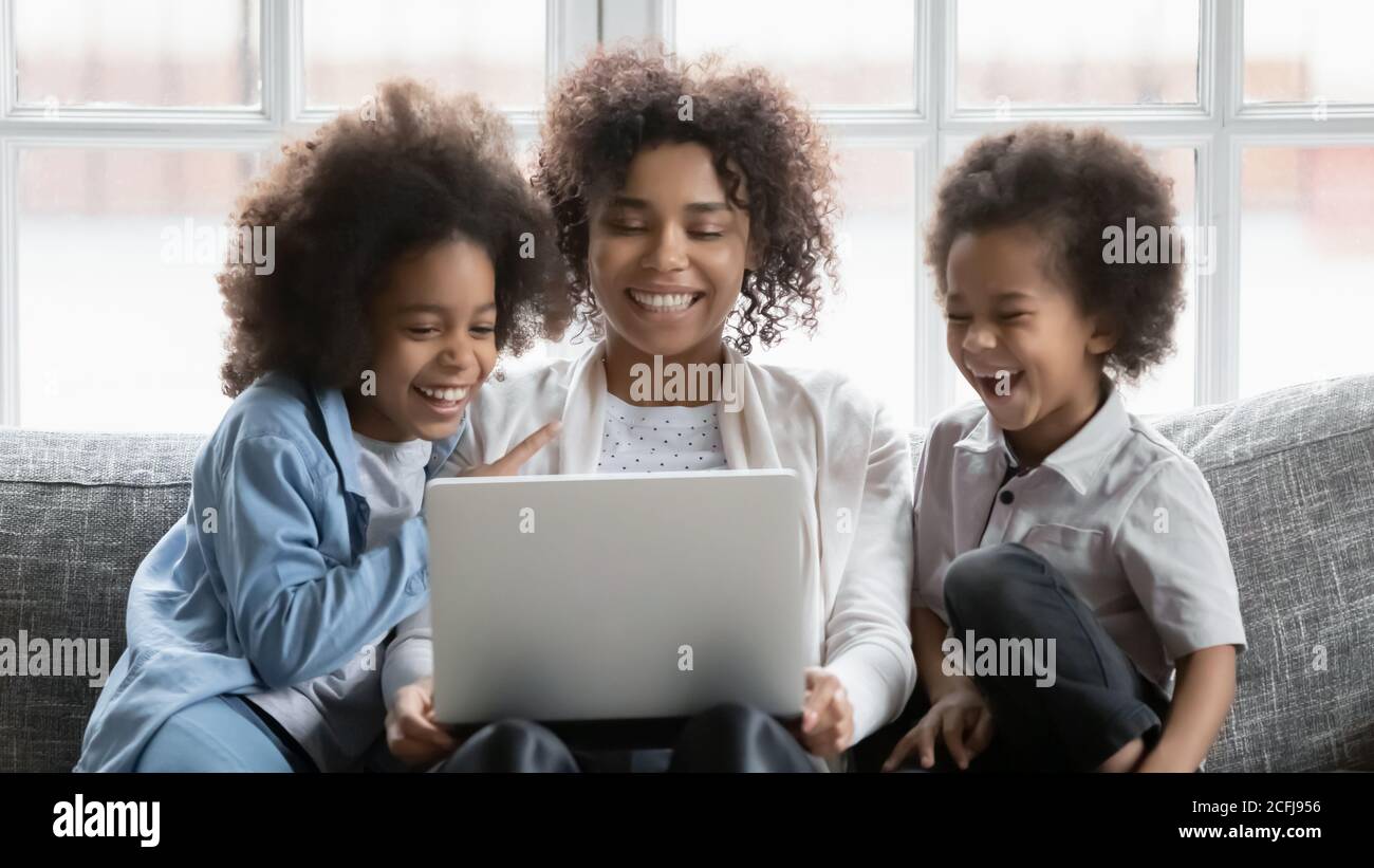 Happy young african woman watching movie on computer with kids Stock ...