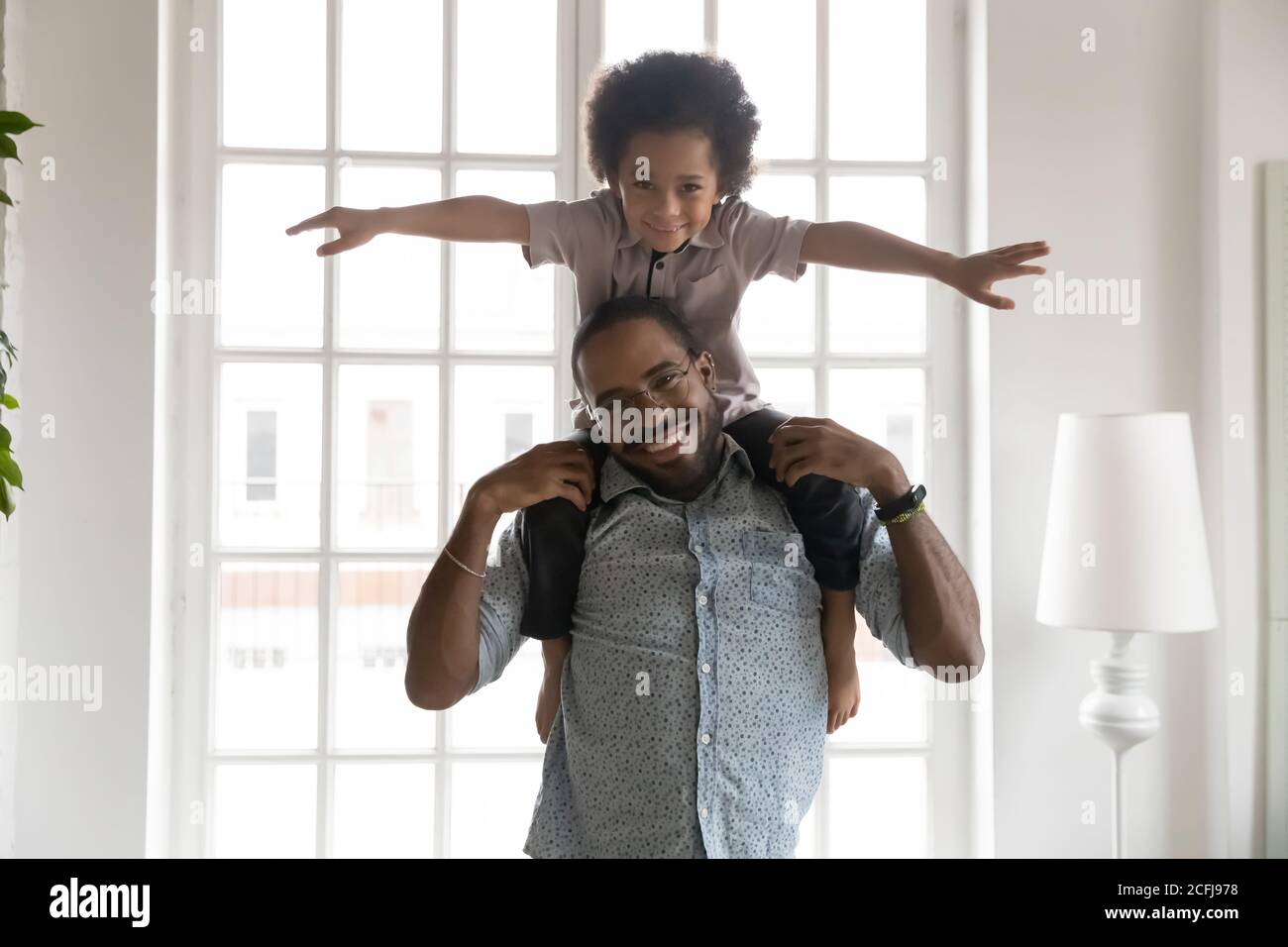 Happy small cute biracial kid boy sitting on father's shoulders Stock ...