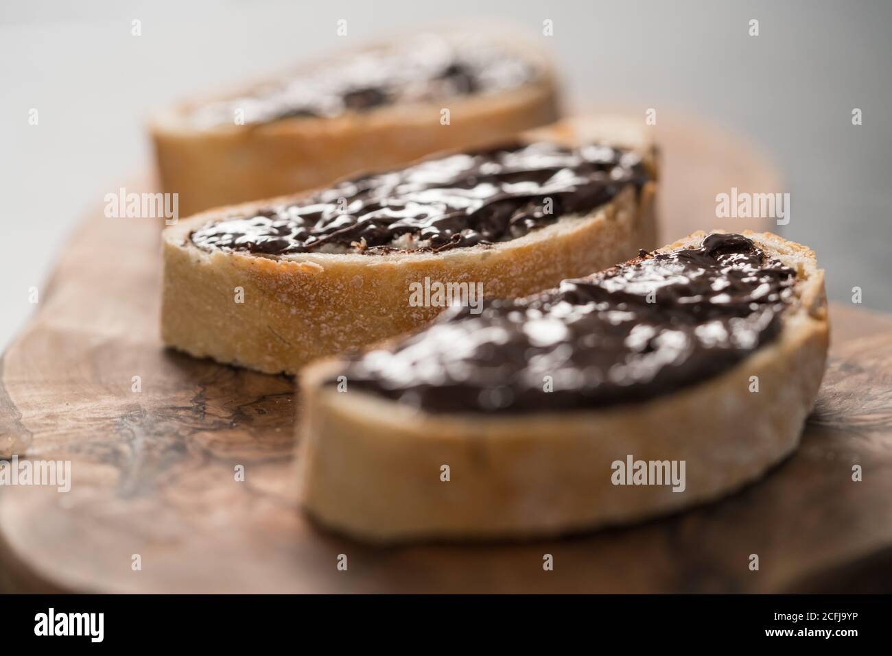 Rustic ciabatta with organic chocolate cream on olive wood board ...