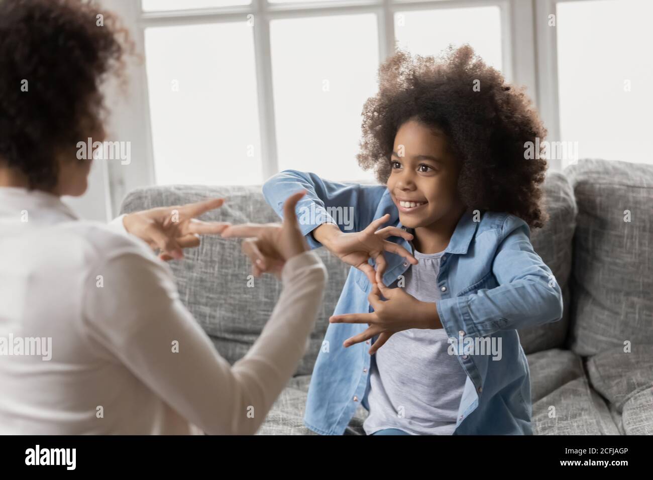 African girl with hearing loss practicing body language with therapist ...