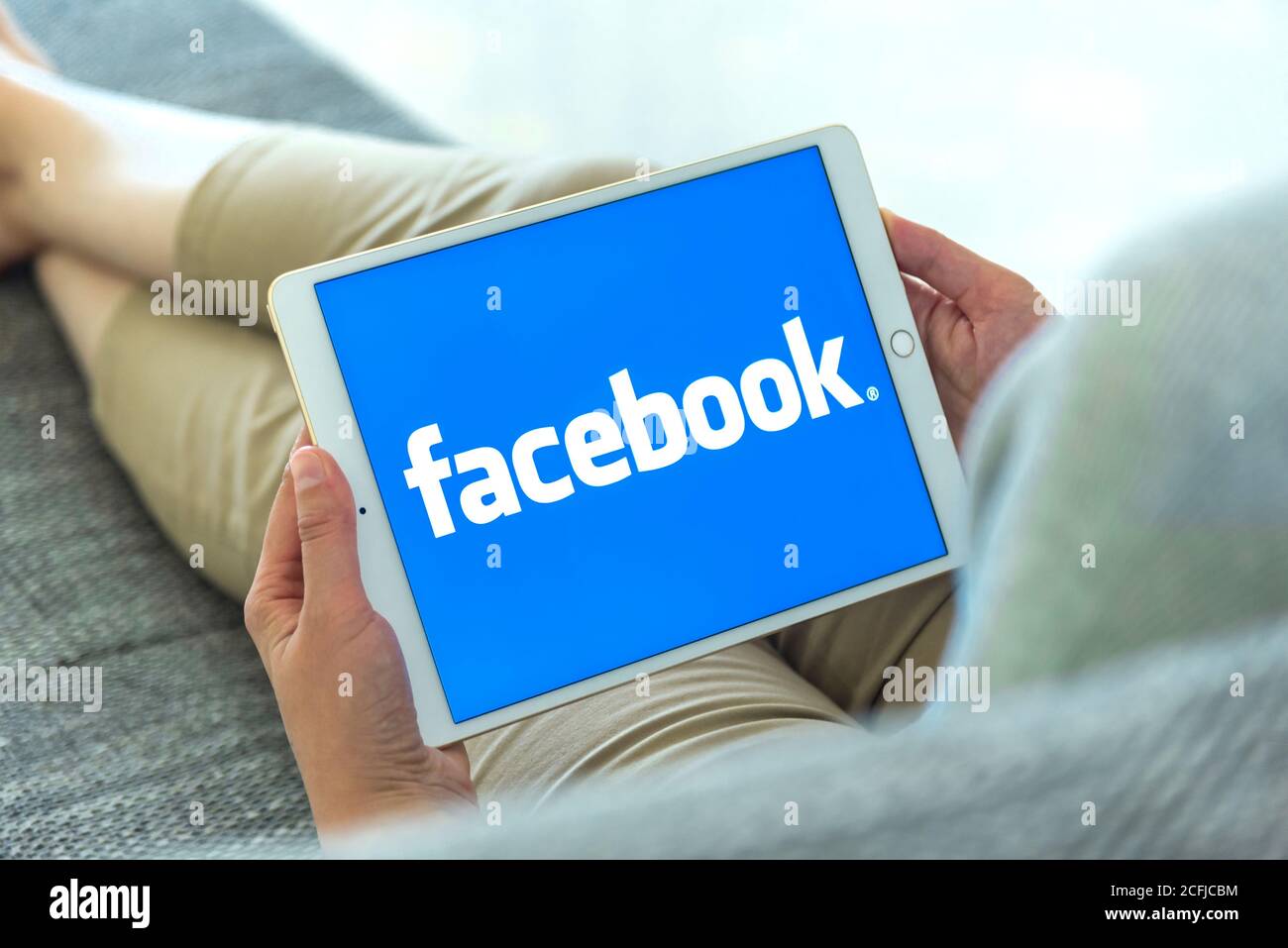Woman Hands using iPad with Facebook homepage on screen. Facebook the ...