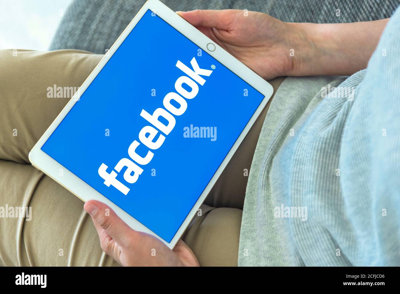 Woman Hands using iPad with Facebook homepage on screen. Facebook the ...