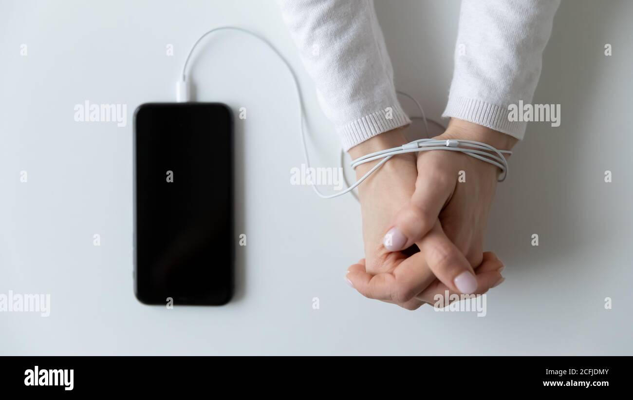 Female hands wrapped in wires cables of smartphone Stock Photo - Alamy