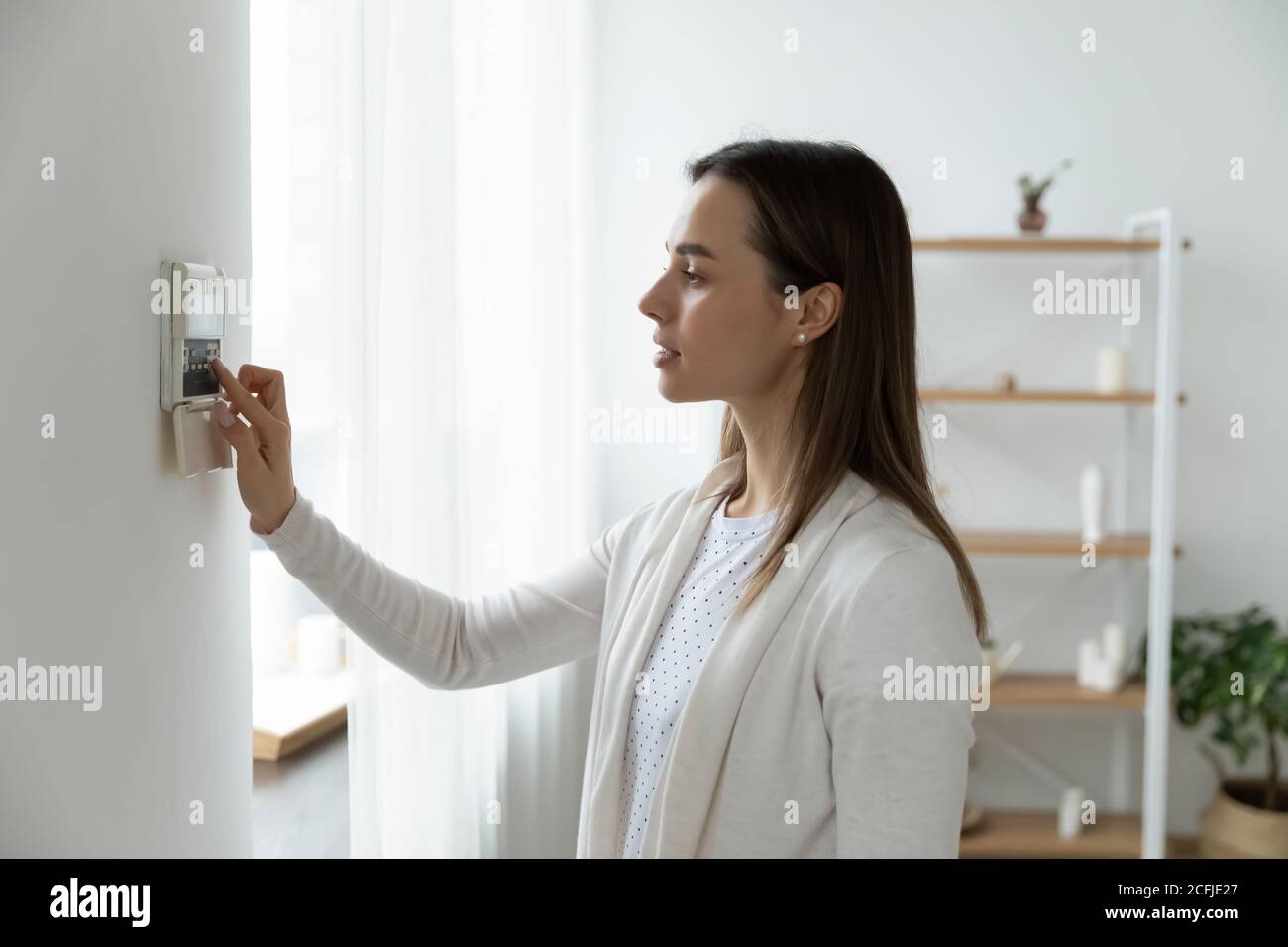 Pleasant young woman using smart home system Stock Photo - Alamy