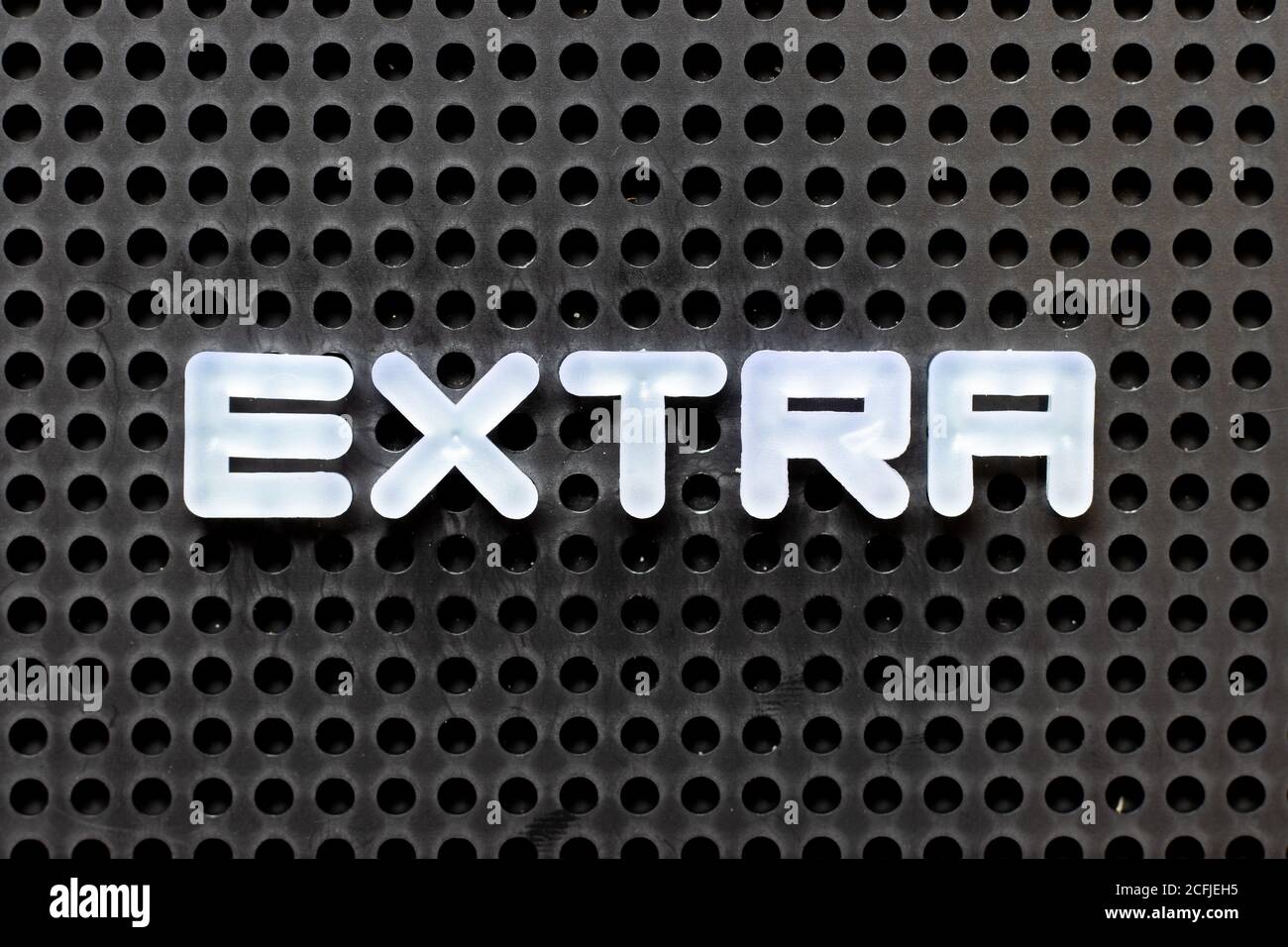 White color alphabet with word extra on black pegboard background Stock ...