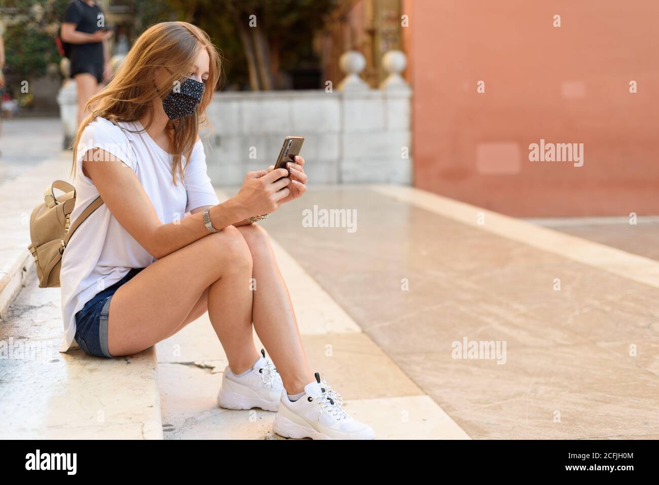 Female with a mask looking through her phone on a street - the new ...