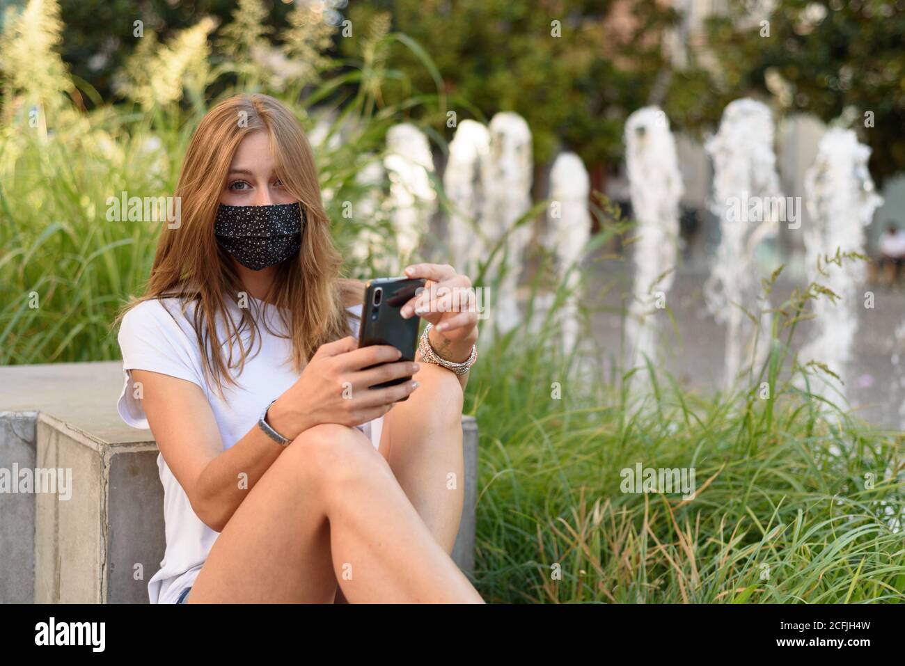 Female with a mask looking through her phone on a street - the new ...