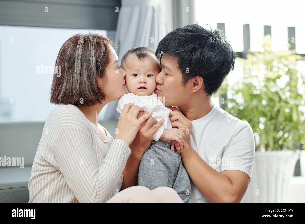 Parents kissing baby Stock Photo - Alamy