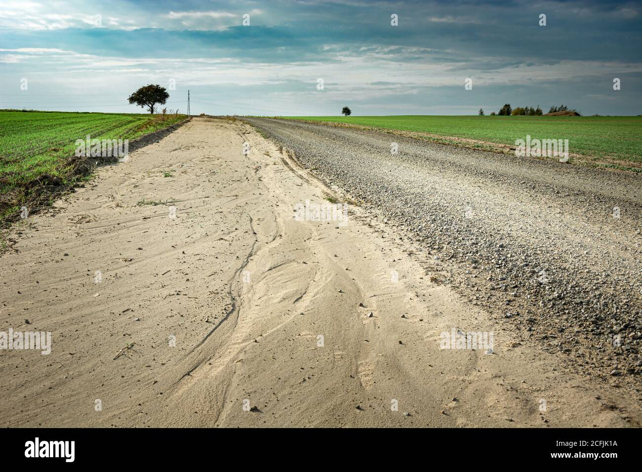 Sandy side of the gravel road and clouds in the sky Stock Photo - Alamy