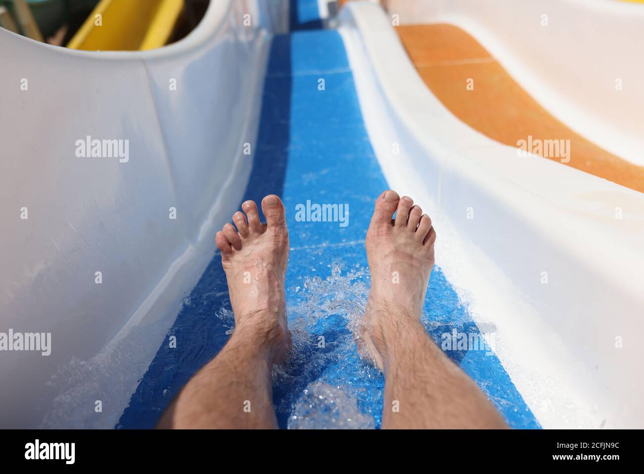 Male feet on background of roller coaster in the water park closeup ...