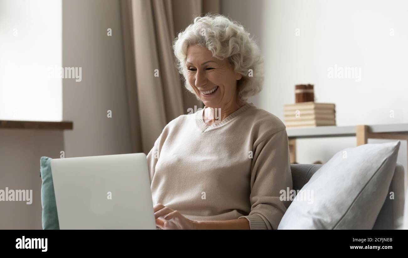 Smiling middle aged woman looking at laptop screen at home Stock Photo ...