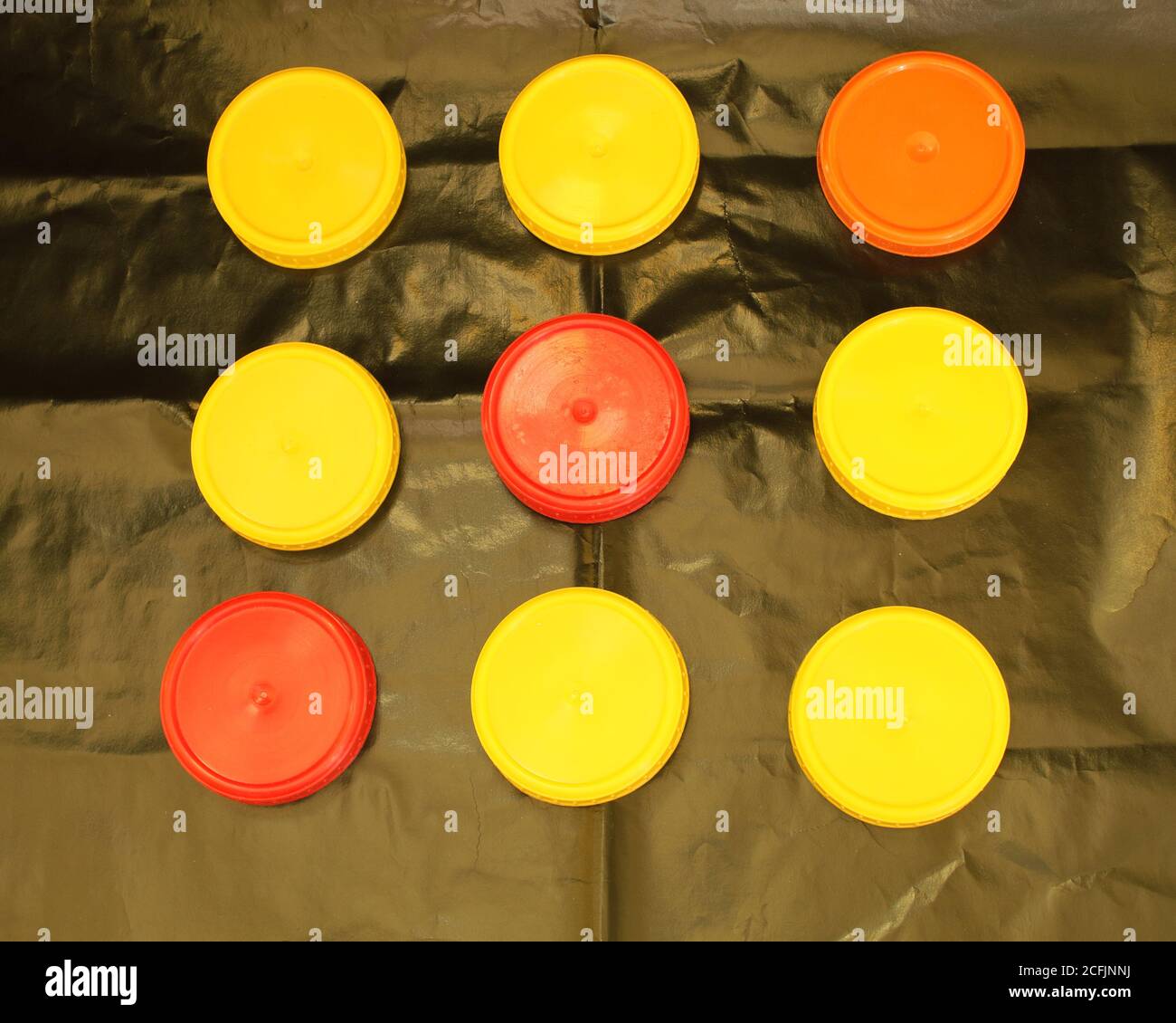 Three red and six yellow plastic round lid for jars on a black ...