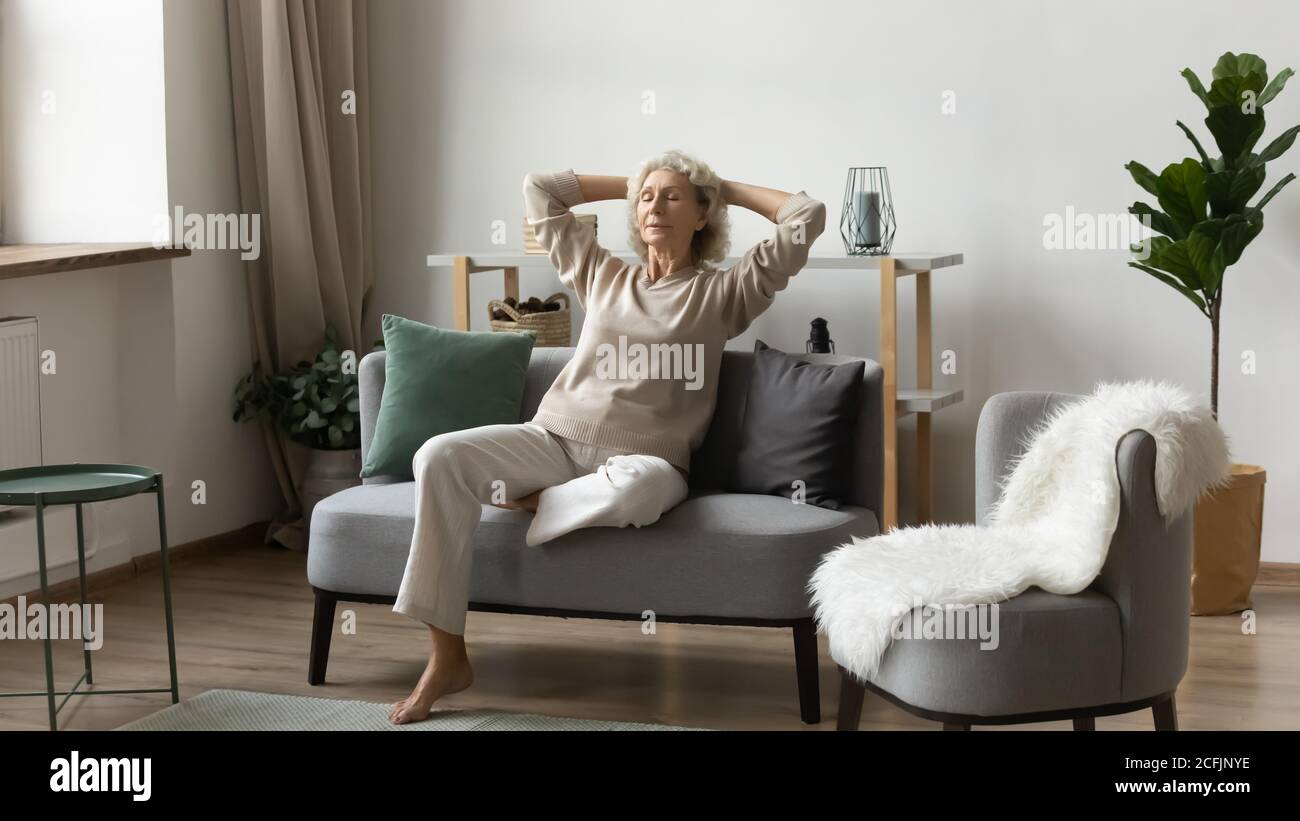 Peaceful Satisfied Mature Woman Relaxing On Comfortable Sofa At Home