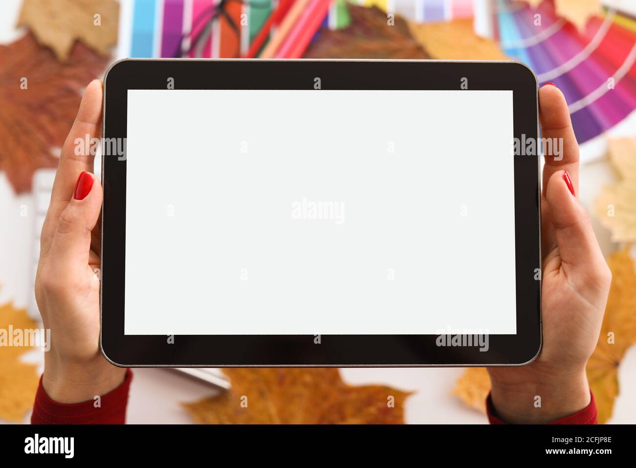 Female hands hold tablet against background of autumn leaves and color ...