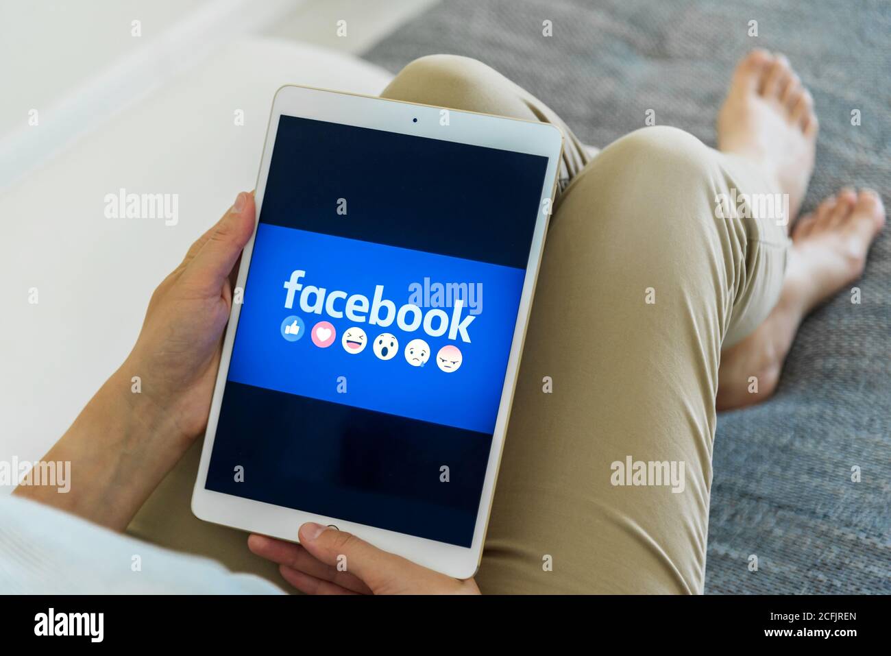 Woman Hands using iPad with Facebook homepage on screen. Facebook the ...