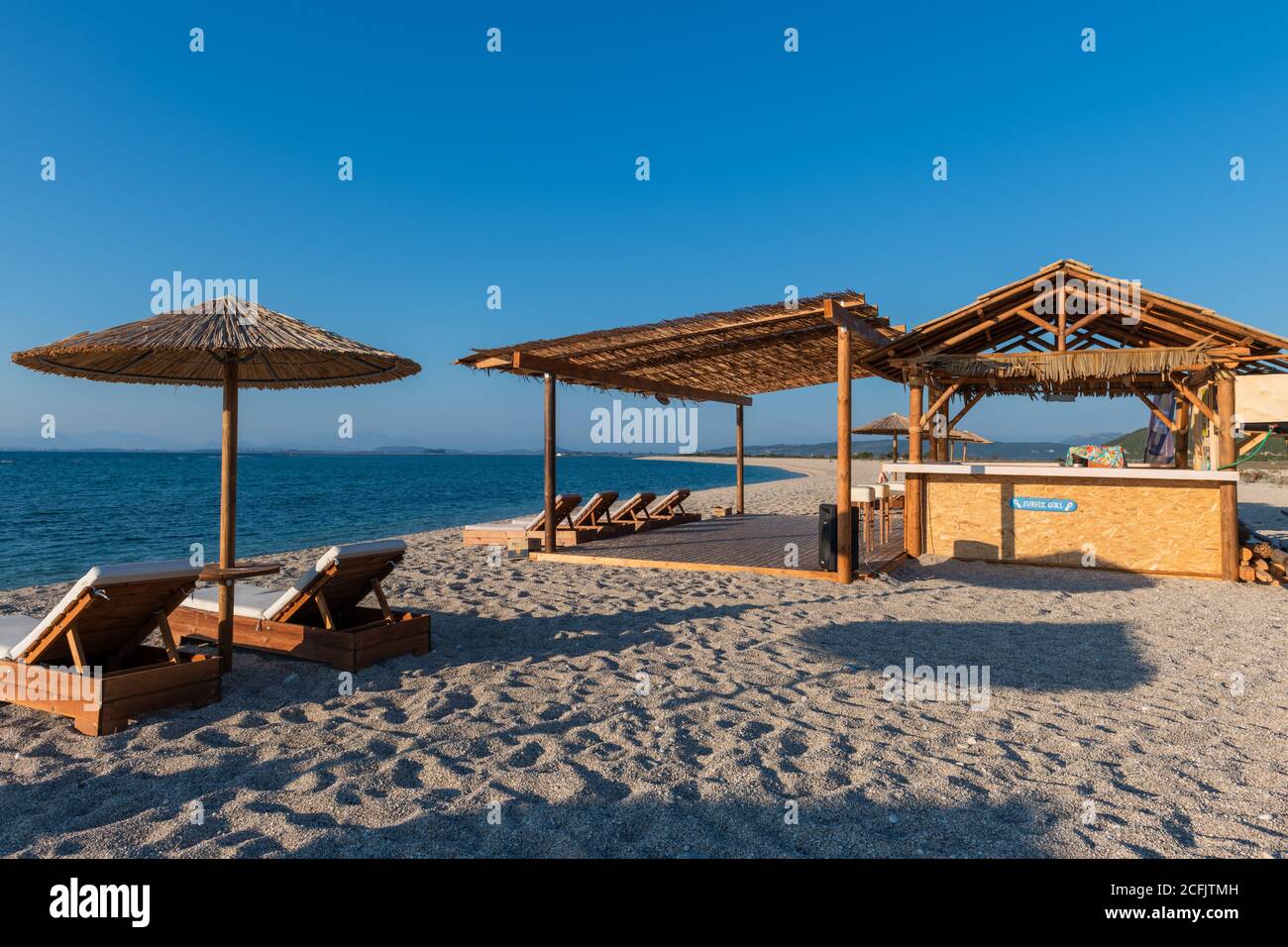 A beautiful deserted long sandy beach in hot summer sun with cloudless ...