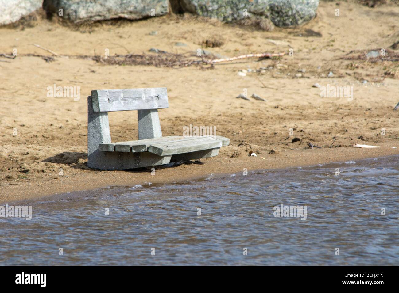 Small wooden bench on the beach surrounded by the sea at daytime Stock ...