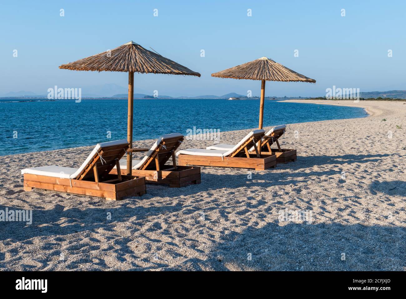 A beautiful deserted long sandy beach in hot summer sun with cloudless ...