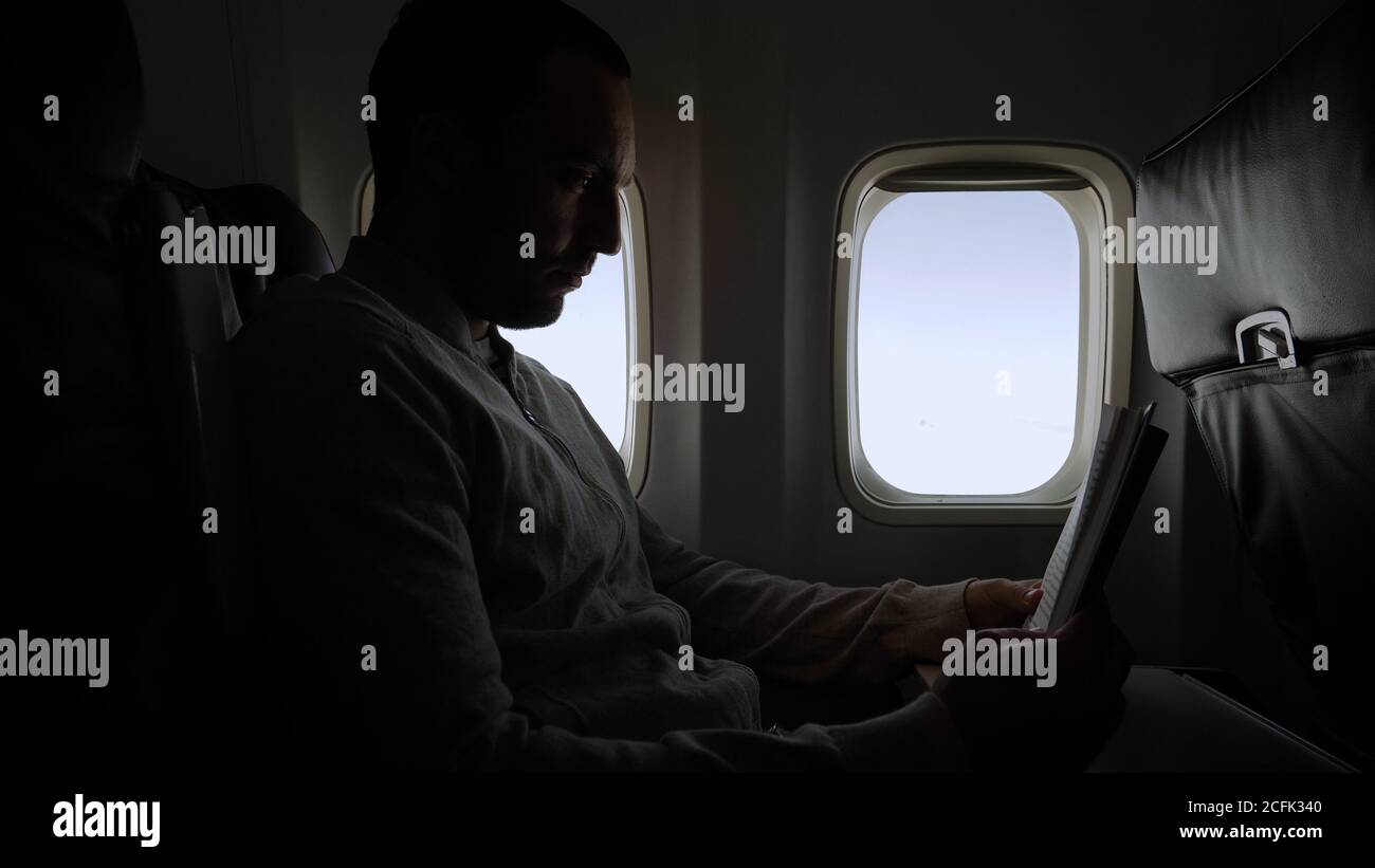 Man reading book during flight Stock Photo - Alamy
