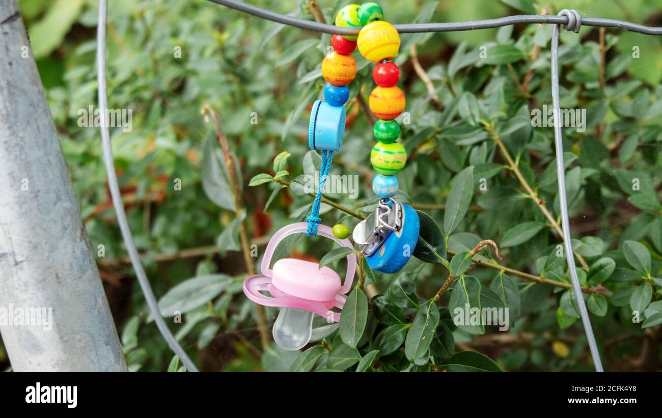 Lost baby pacifier with a colorful chain hanging on the fence Stock ...