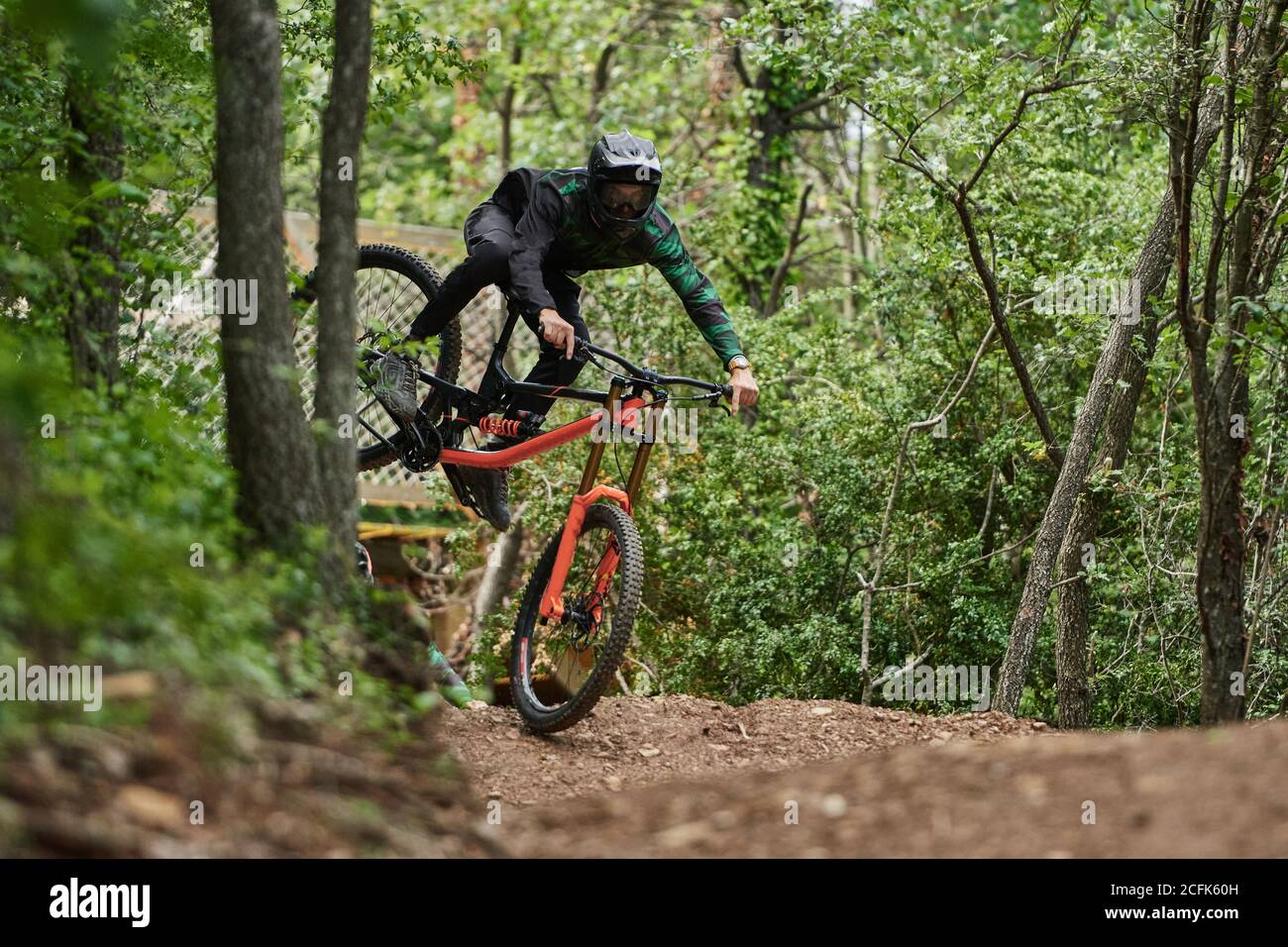 Brave male biker in protective helmet riding bicycle for downhill in ...