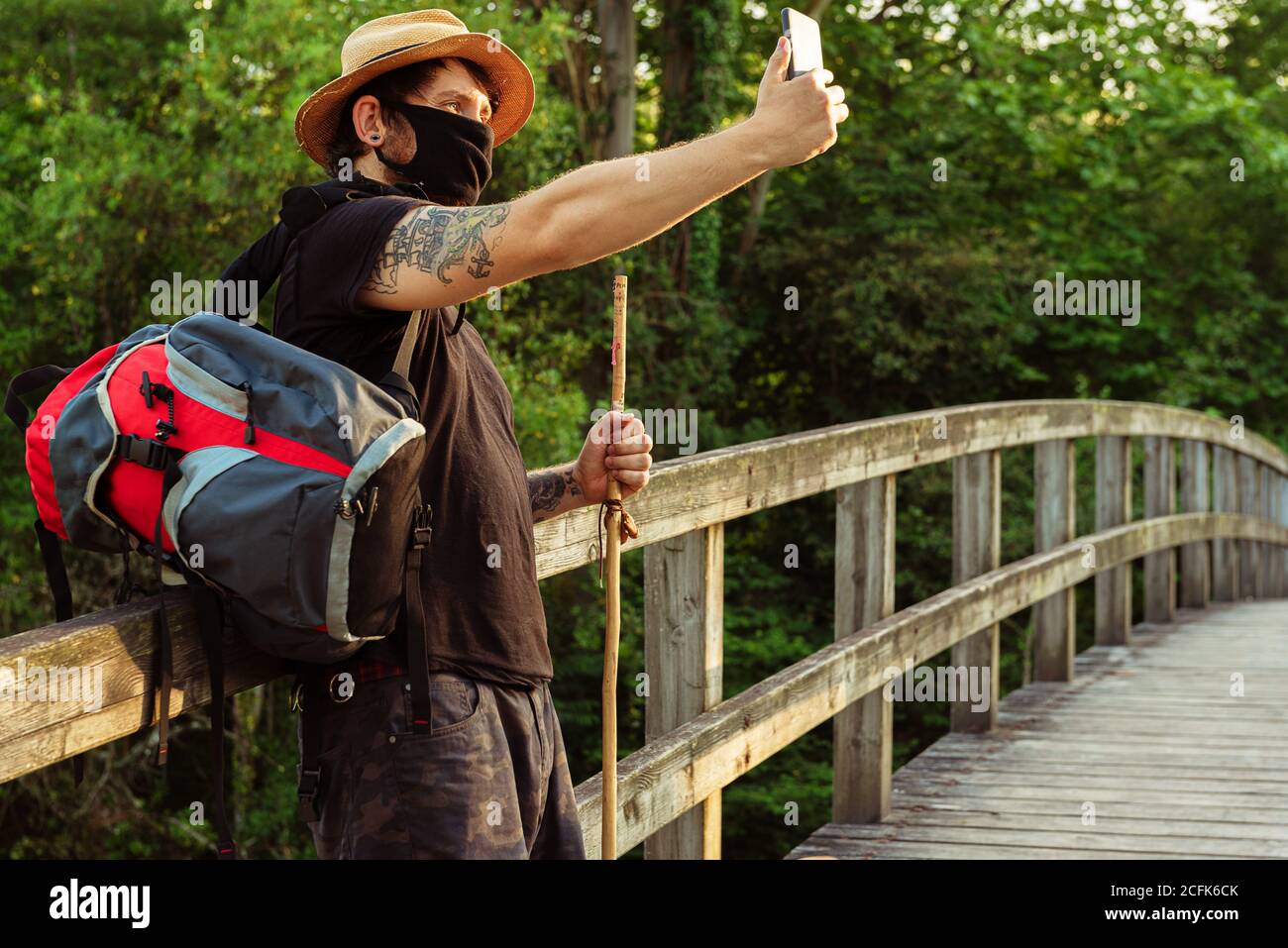 Side view of male wanderer with backpack and wooden stick standing on ...
