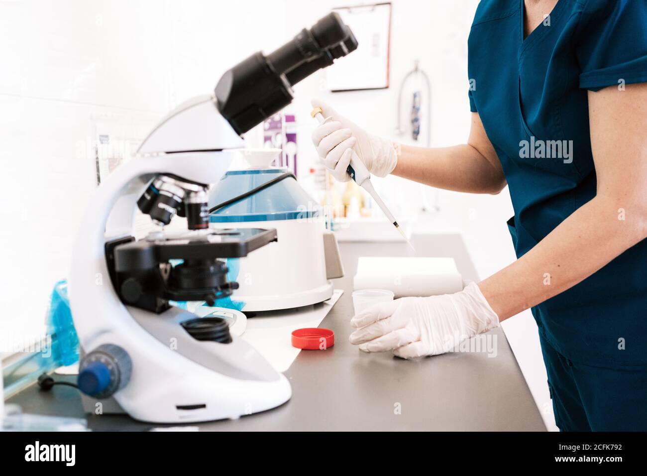 Side view of anonymous person in latex gloves analyzing urine sample ...
