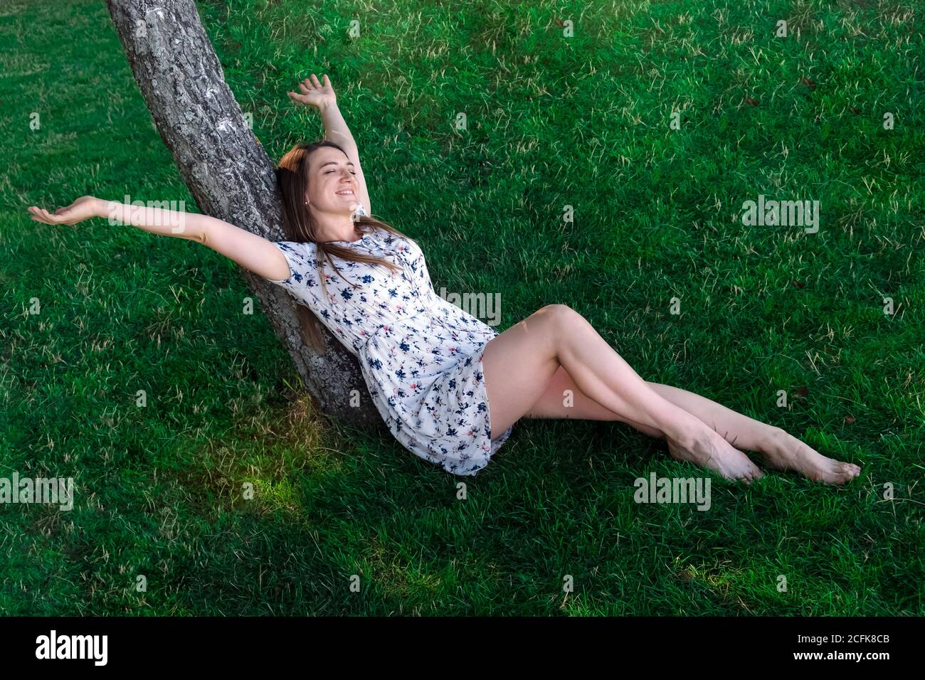 Woman sitting against tree trunk hi-res stock photography and images ...