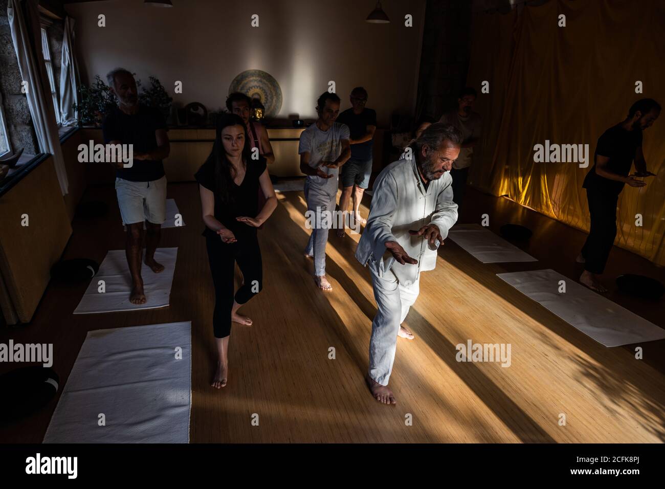 Group of people with instructor performing flowing movements with ...