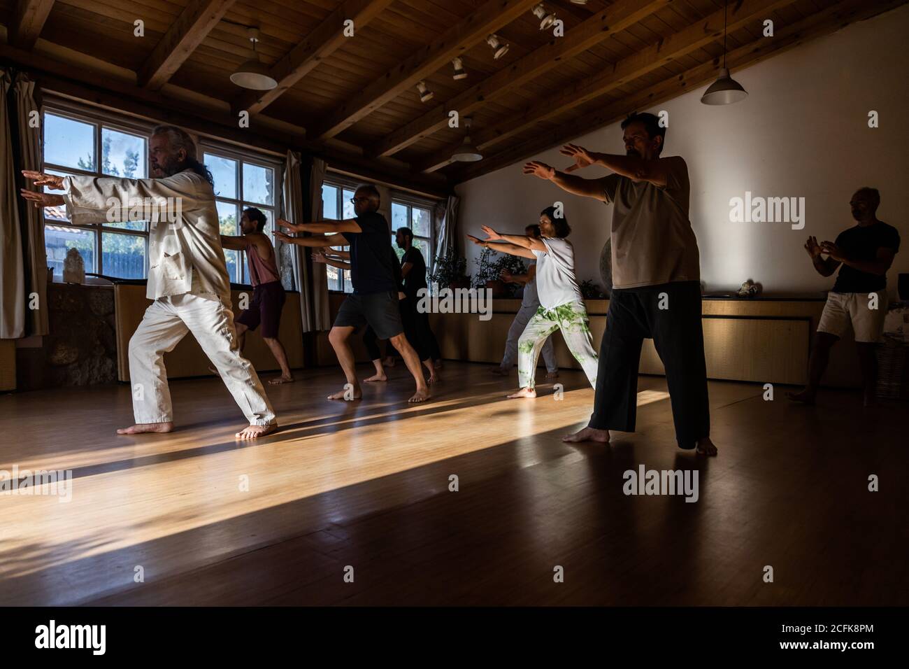 Group of people with instructor performing flowing movements with ...