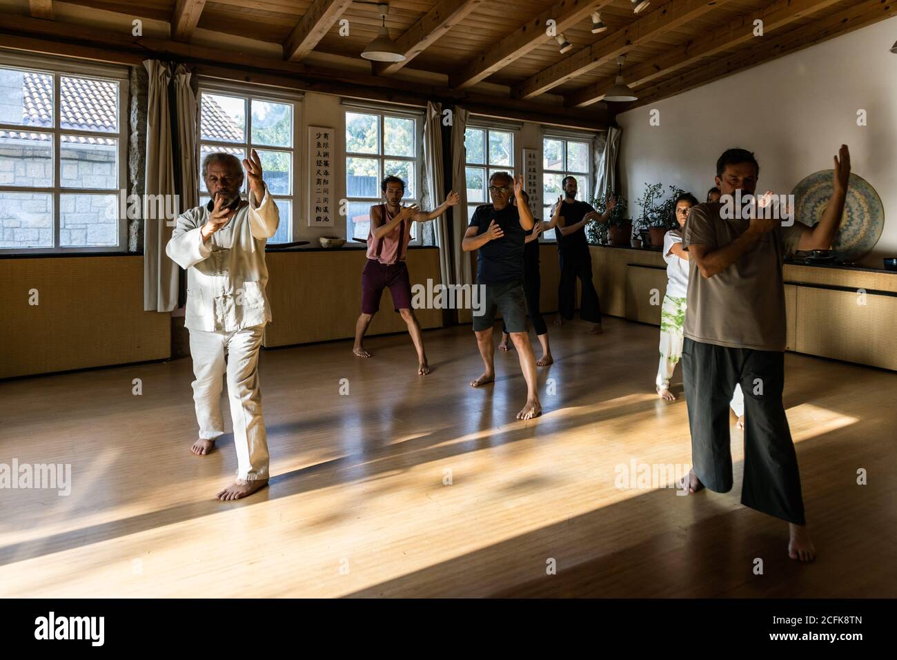 Group of people with instructor performing flowing movements with ...