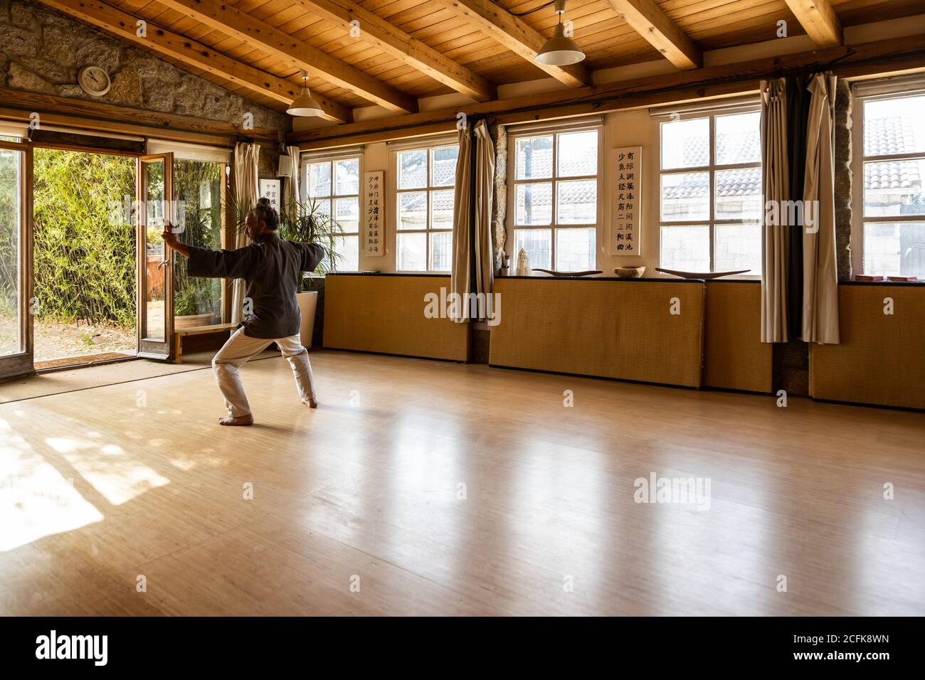 Full body back view senior ethnic male doing traditional chi kung movements during practice in ...