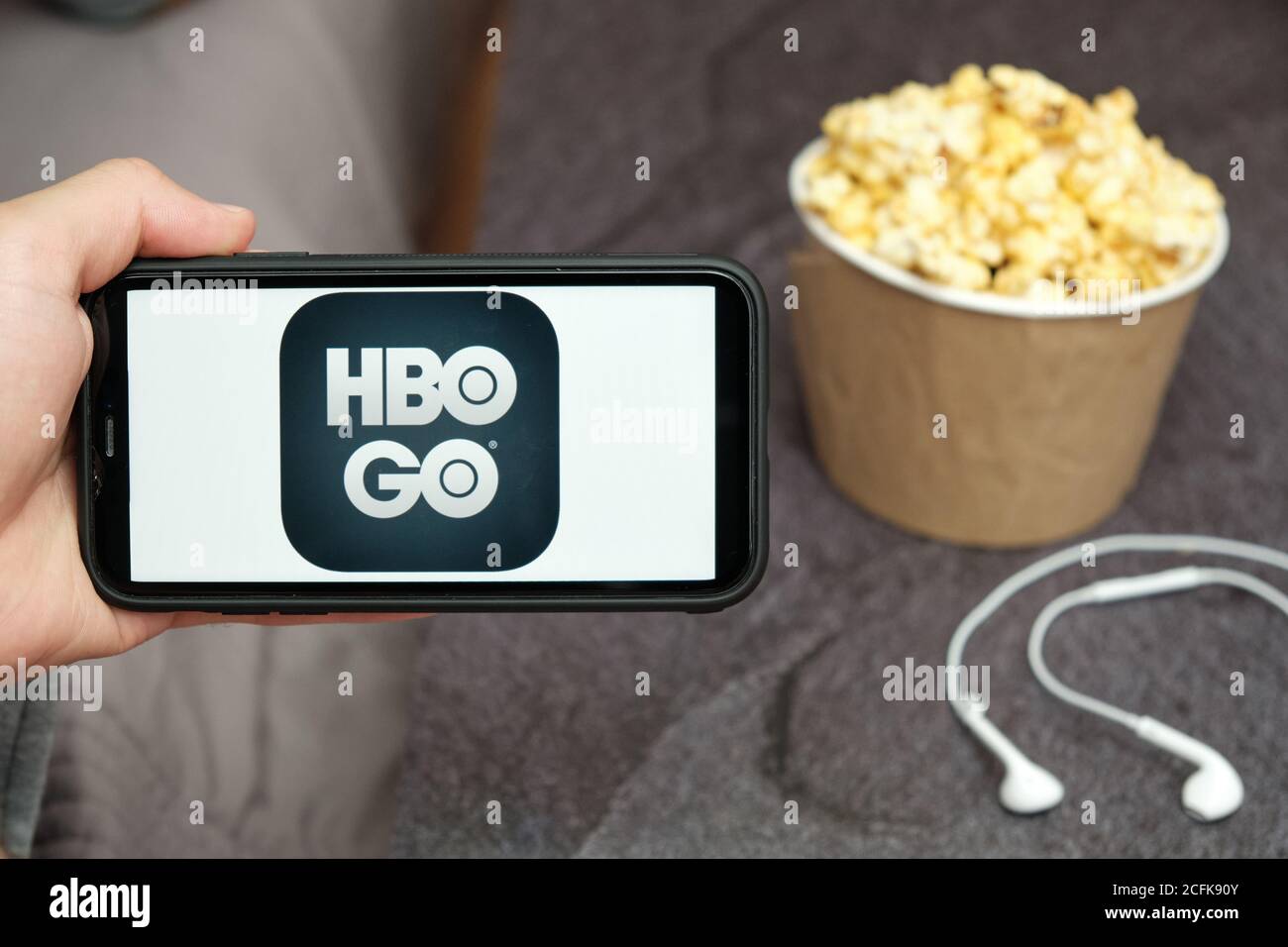 Close up mans hand holding a mobile phone with HBO GO logo with Apple ...