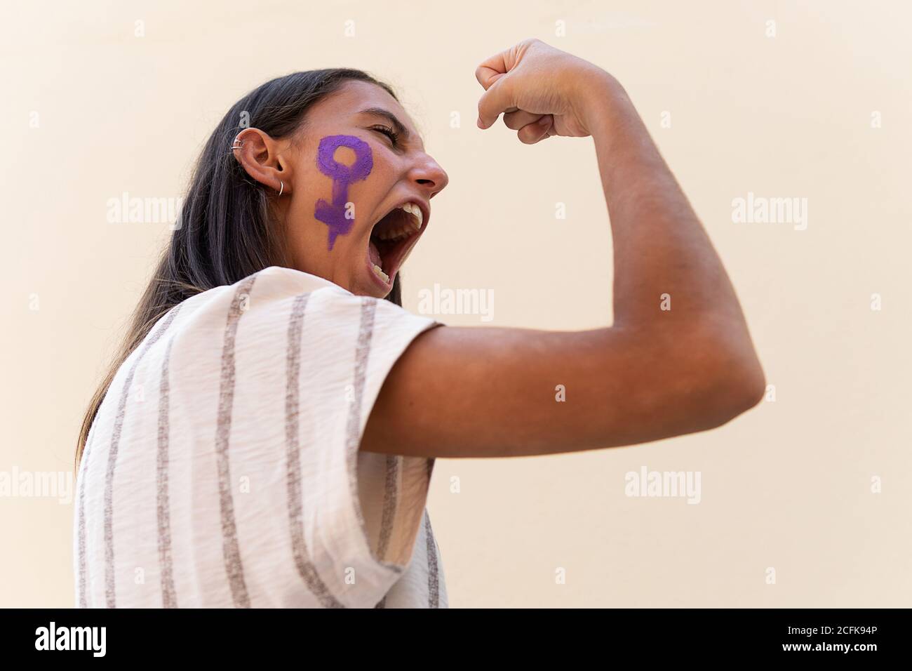 Side view low angle of determined female with gender symbol on face ...