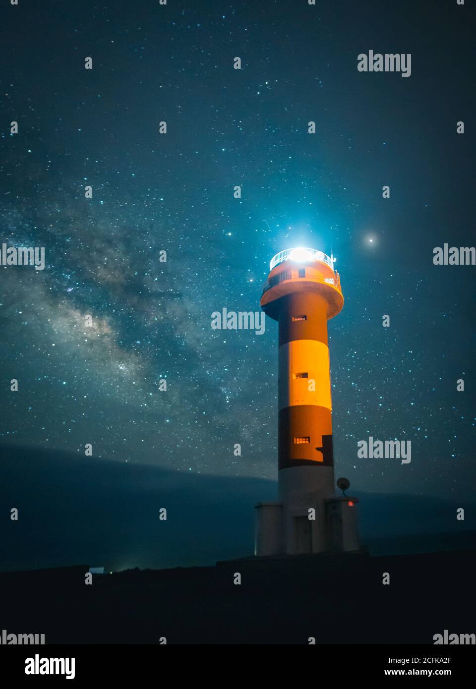 Low angle of lighthouse tower with glowing light against starry sky on ...