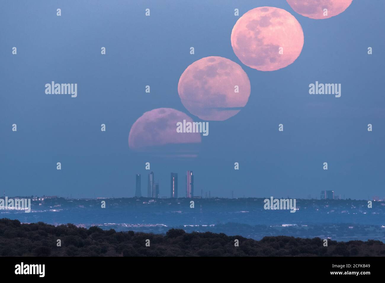 Large red moons shining on blue night sky over skyscrapers of modern ...