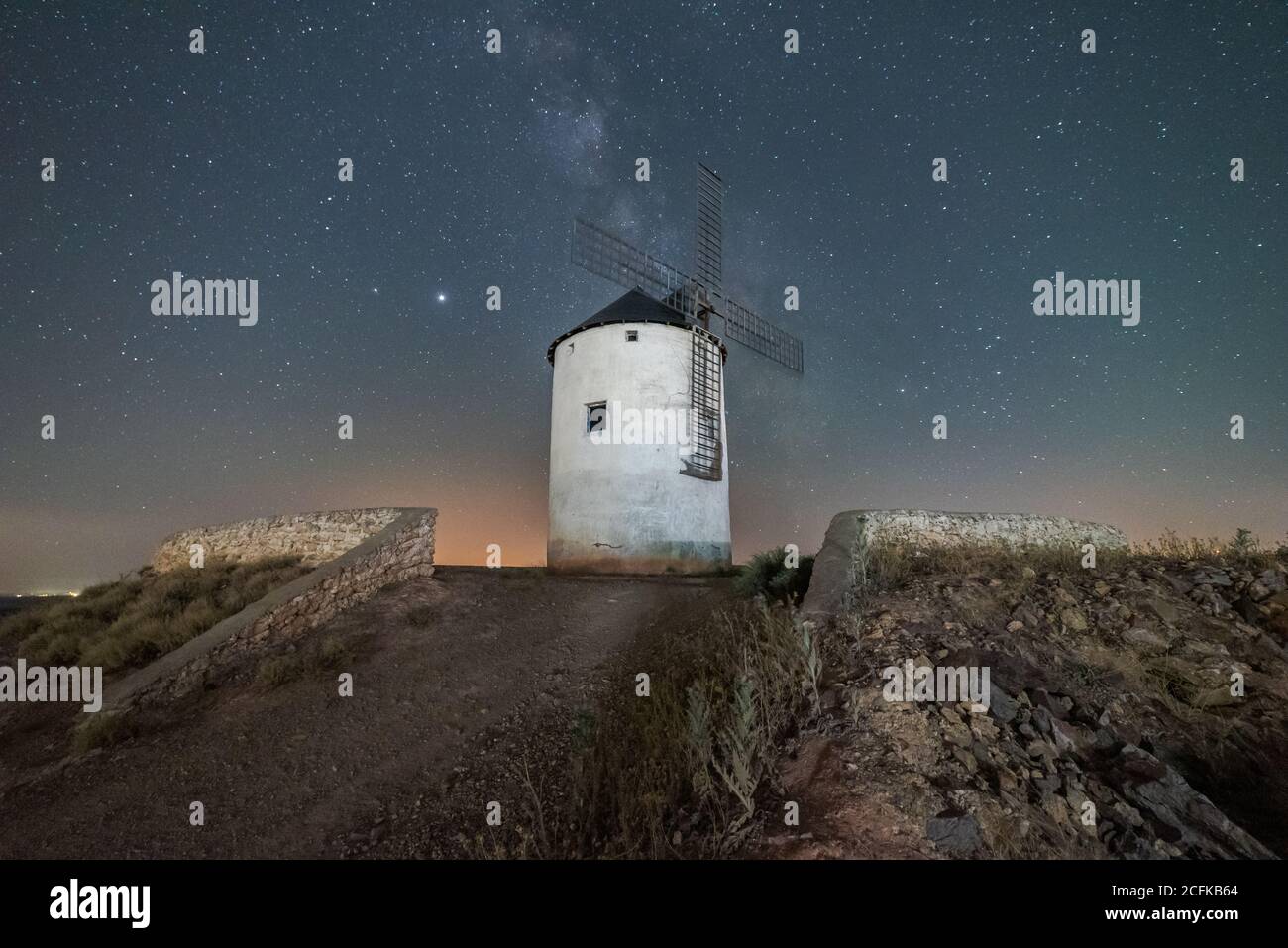 Low angle of old white windmill tower located on hill against starry ...