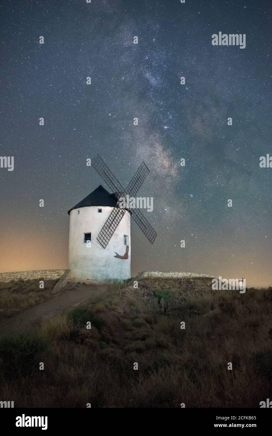 Low angle of old white windmill tower located on hill against starry ...