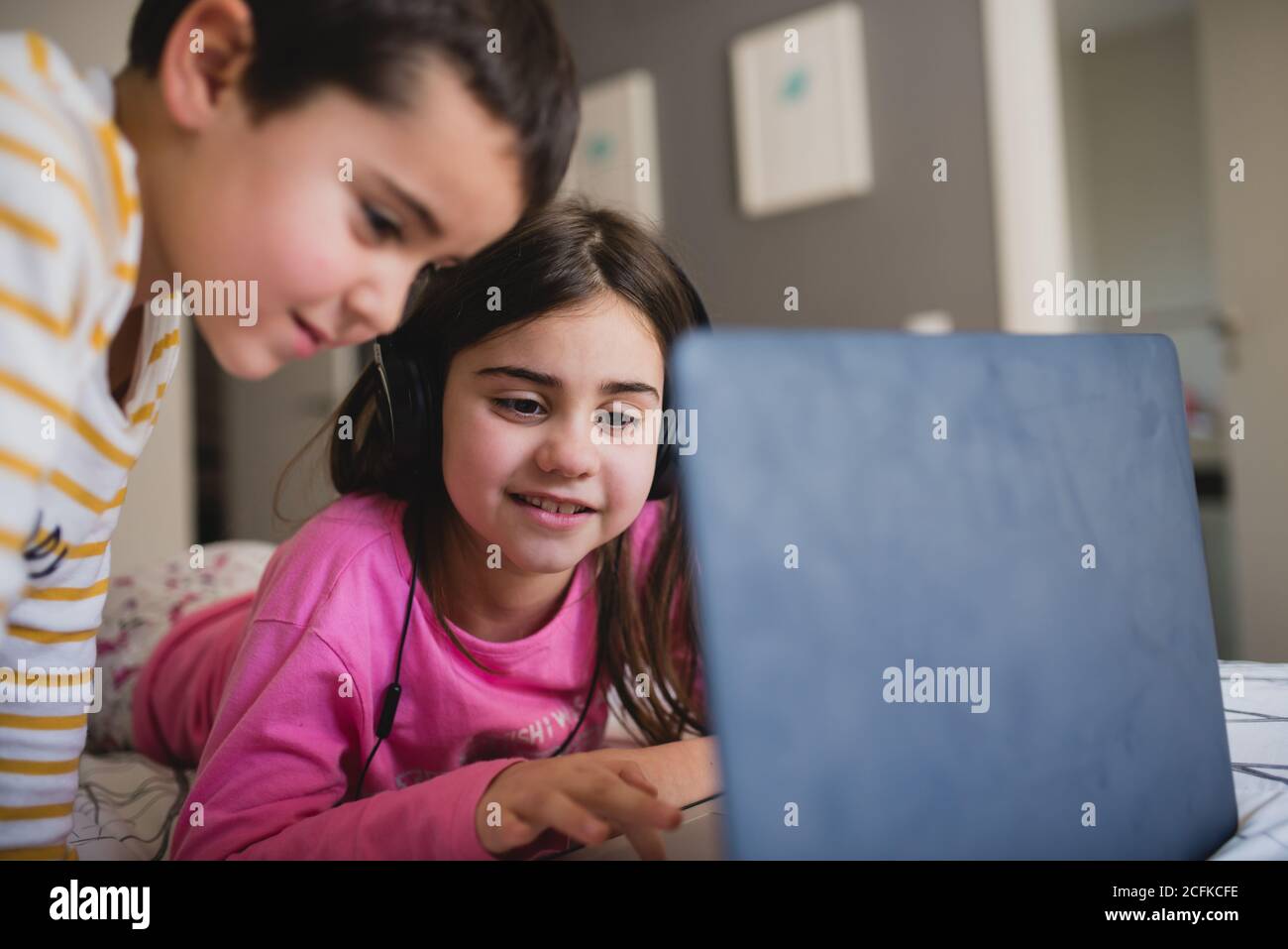Happy little sister and brother having fun and playing game on laptop ...