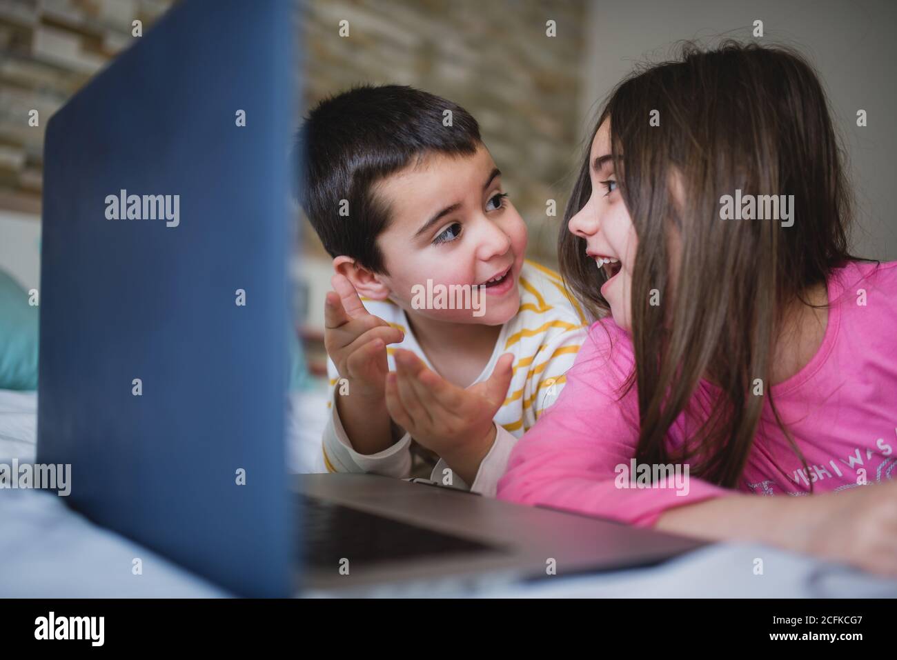 Happy little sister and brother having fun and playing game on laptop ...