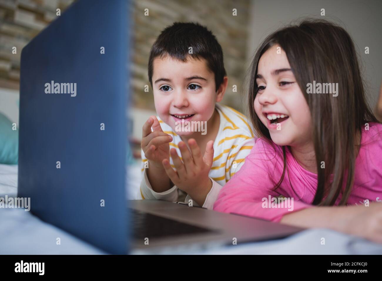 Happy little sister and brother having fun and playing game on laptop ...