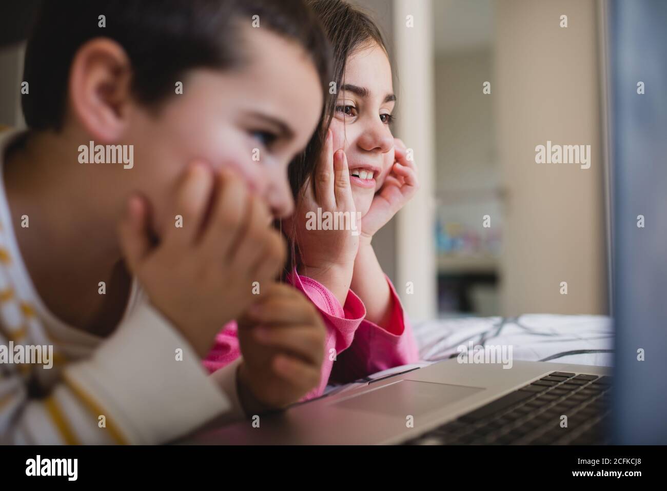 Happy little sister and brother having fun and playing game on laptop ...