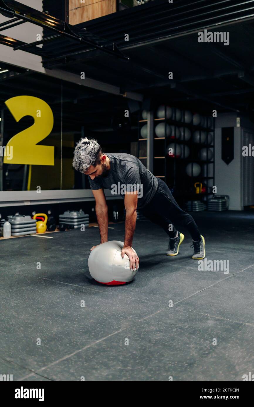 Full length of strong determined athletic male doing plank exercise ...