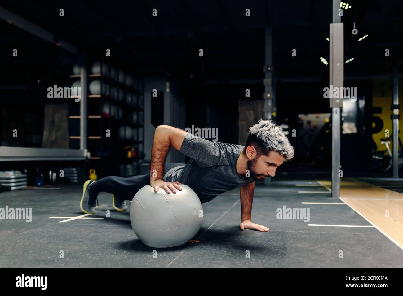 Full length of strong determined athletic male doing plank exercise ...